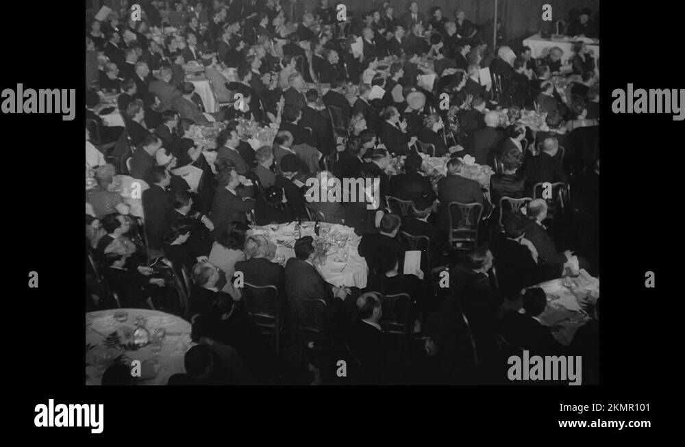 1940s A crowd of people sitting around tables listen to a speech. The ...
