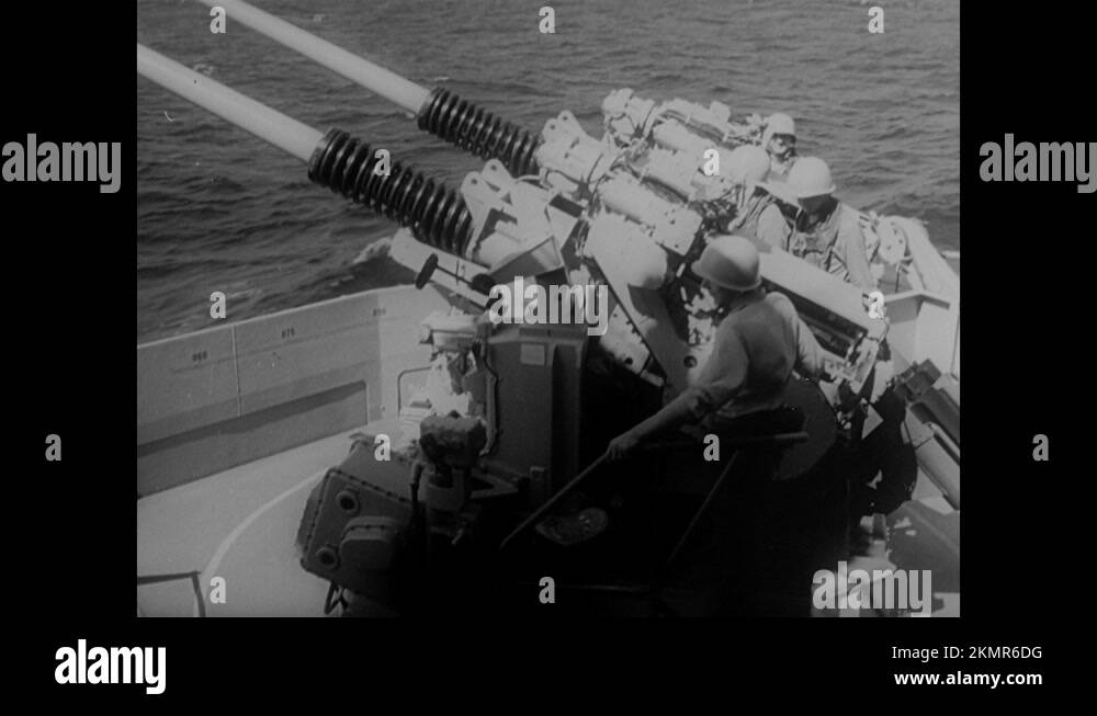 1960s: Navy sailor looking into binoculars. Bow of battleship. Men on ...