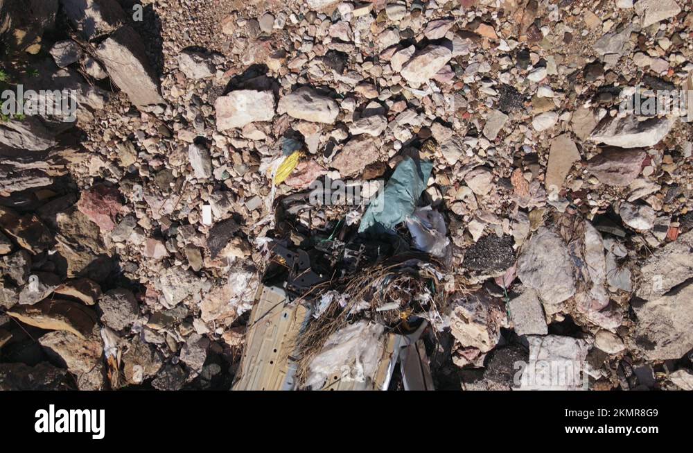 Dump with garbage and broken car on the rocks among cliffs on slope or ...