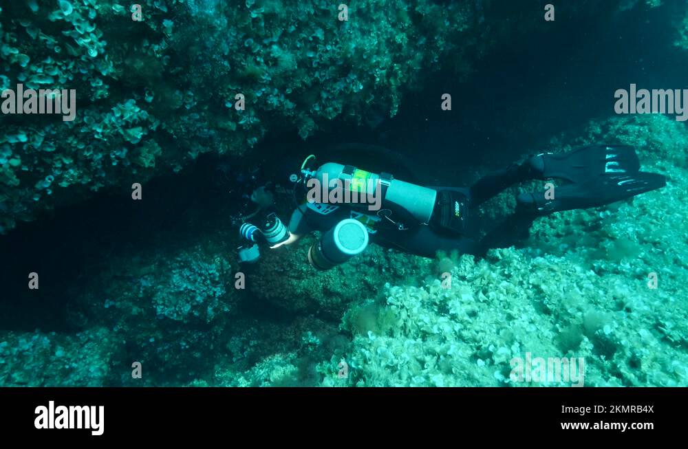 Scuba diver photographer swims into the cave, 4K - 60 fps. Cave diving ...