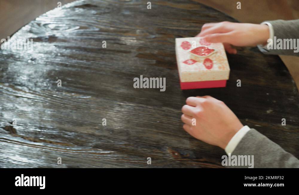 A man takes a gift box from under the table and puts it on the table in ...