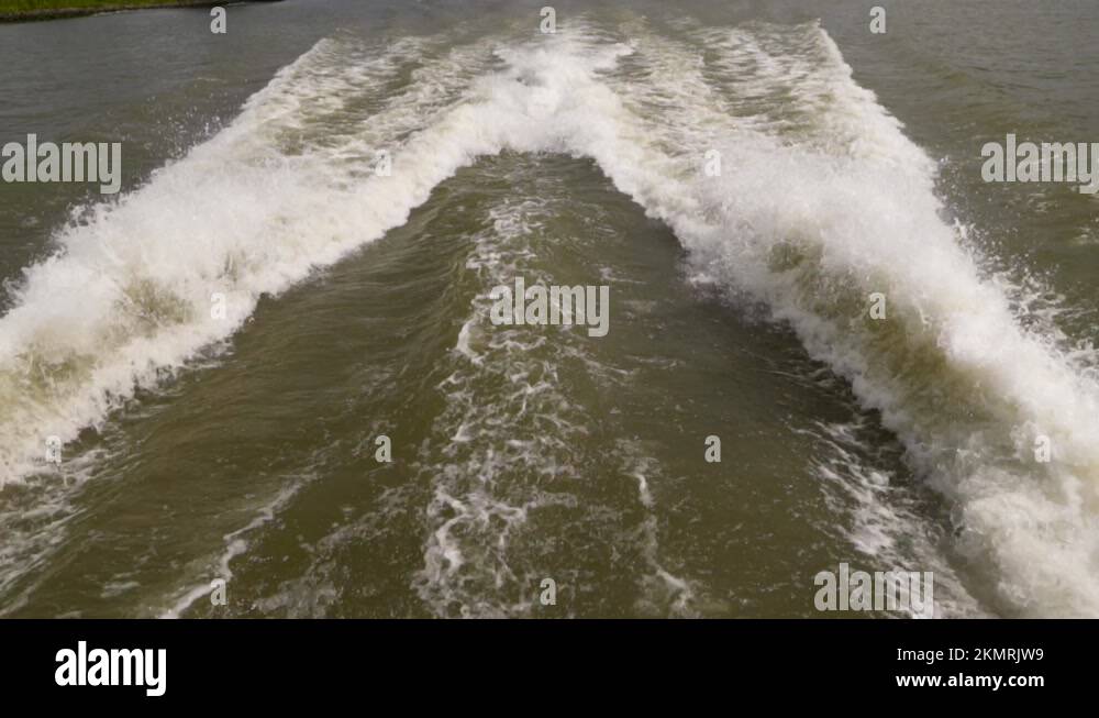 A speed boat and its engine propellers churn the water into high waves ...