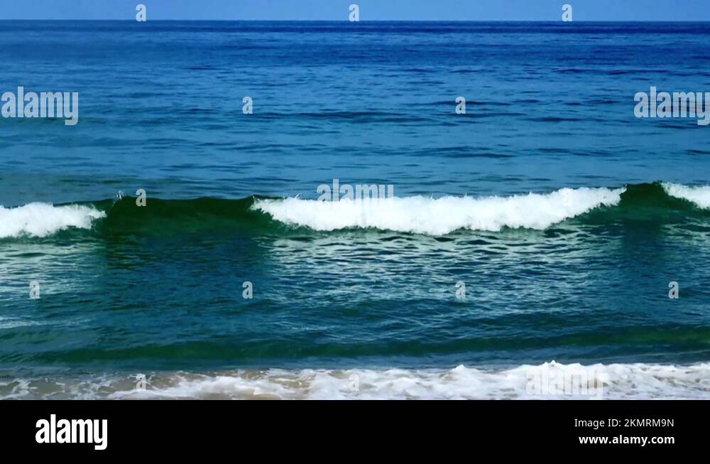 Ocean wave n cyan green sea water with white foam on sunny clear blue ...