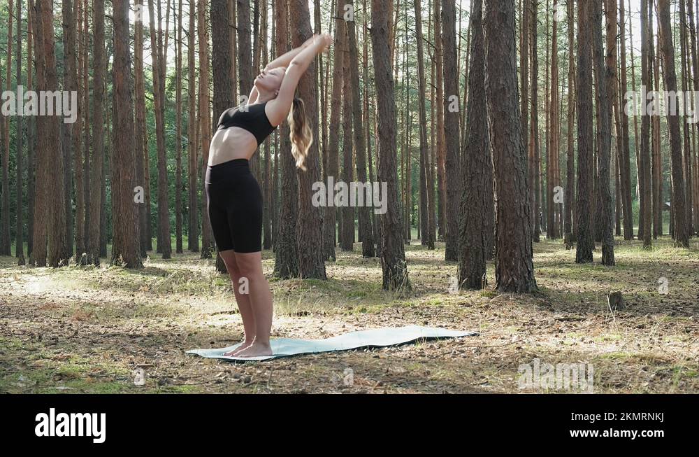 flexible fit female practices yoga, performs surya namaskar at sunny ...
