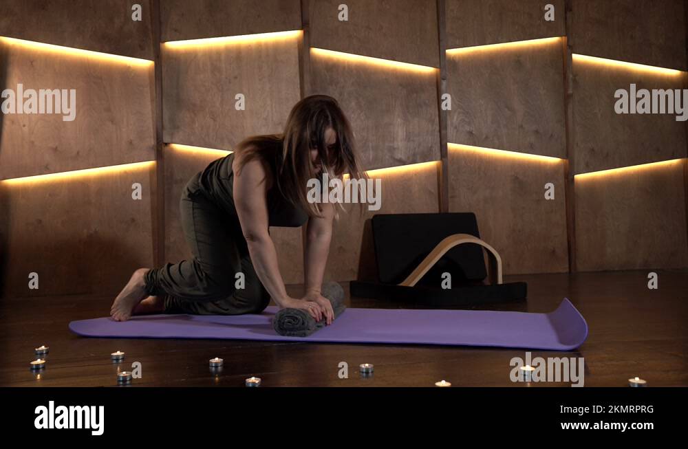 a woman is sitting on her knees on a sports mat against a wooden wall ...