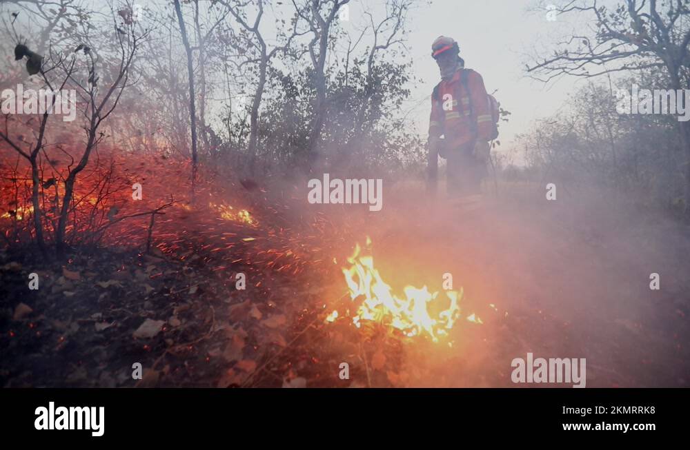 Sparks and burning embers fly as a fireman uses a blower to control the ...