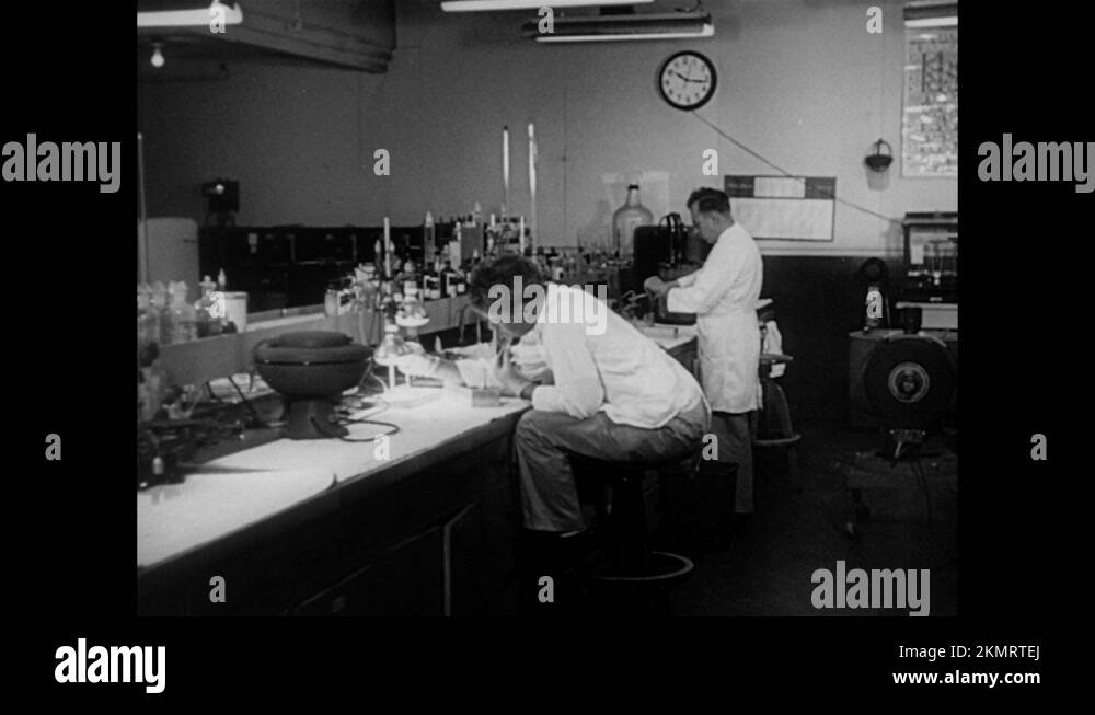 1940s: Two people conduct experiments in lab. Gauge, lab equipment ...