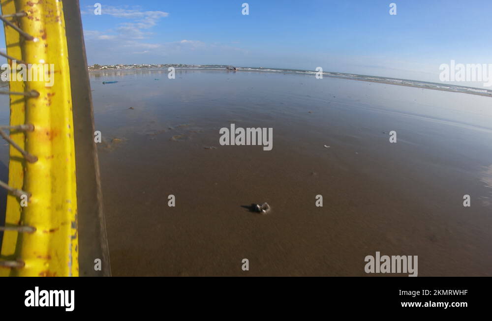 Action point of view riding a moped along a heavily polluted beach in ...