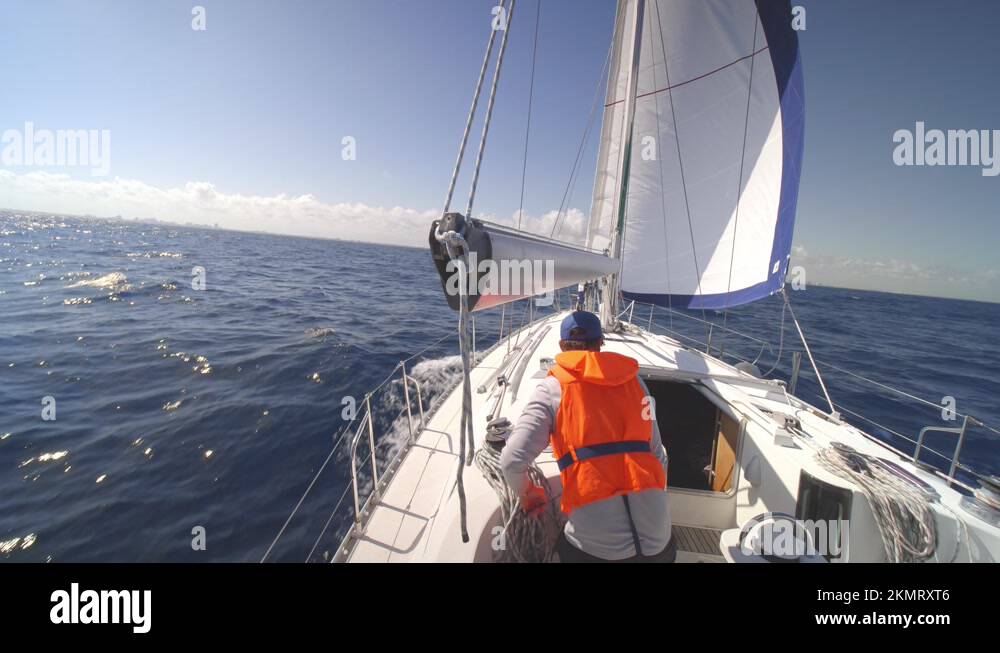 Back of Male in Sailboat Working on Sails With Rope and Winch With ...