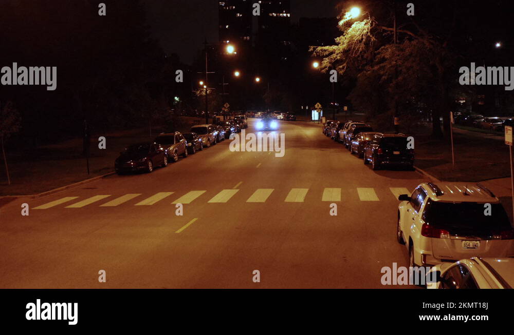 Car is driving through an intersection with the car headlights on Stock ...