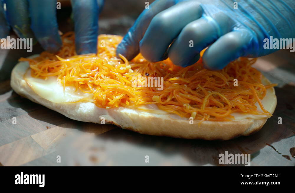 Takeaway preparation of fast food sandwich, chef in gloves stuffing hot ...