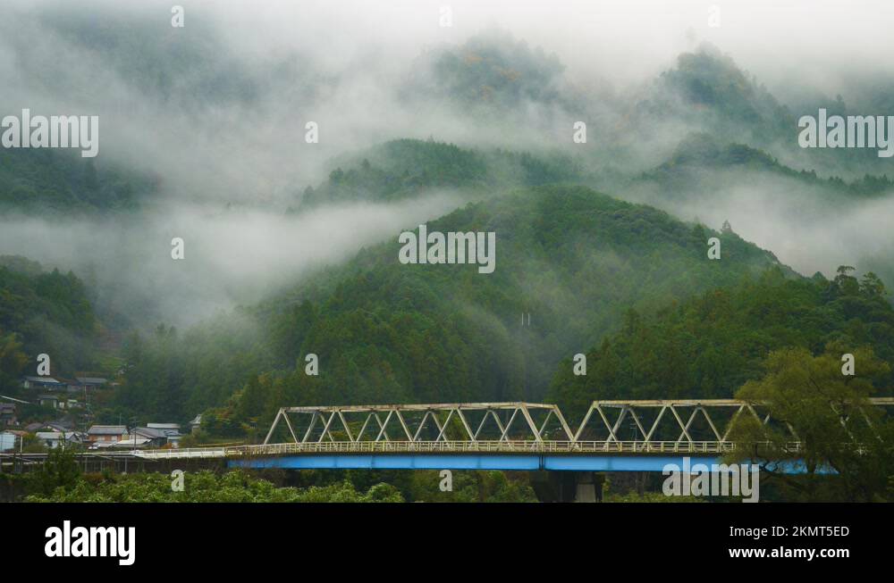 Static, bridge afore forrested hillside shrouded in fog, Japan Stock ...