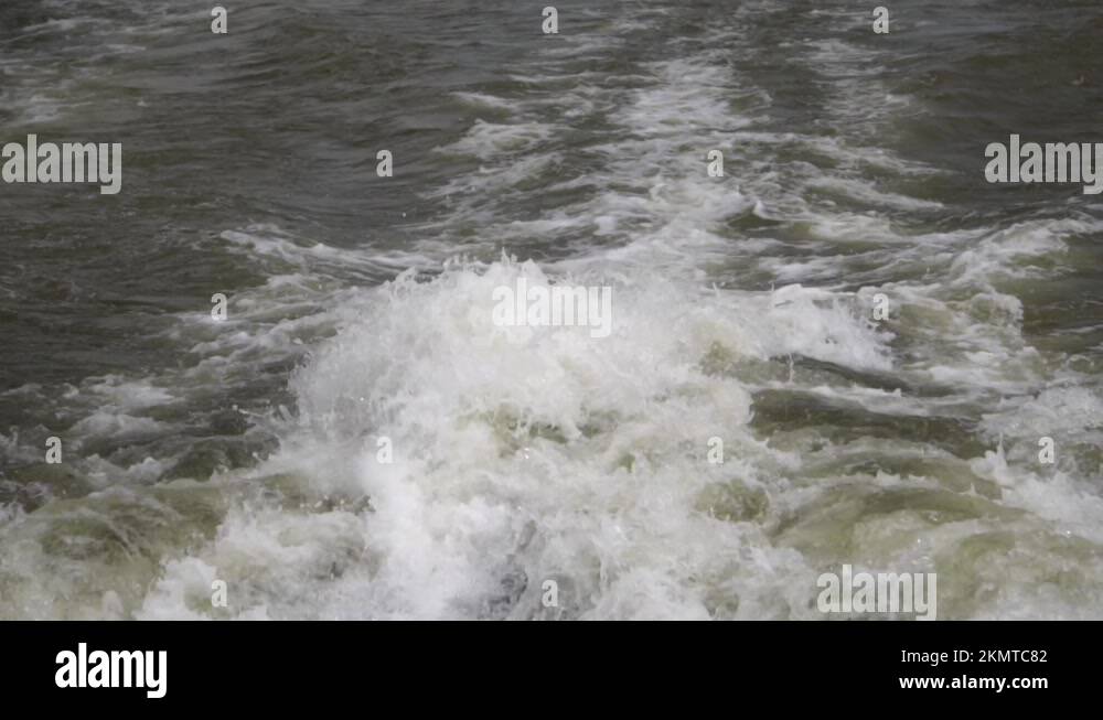A speed boat and its engine propellers churn the water into high waves ...