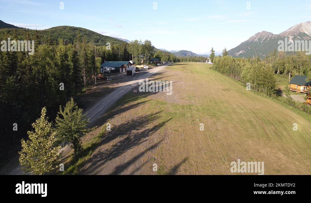 Drone footage slowly flying over a private grass runway with homes and ...