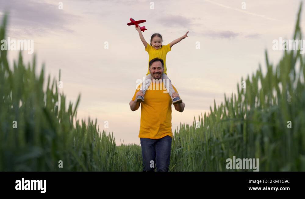 A father with a small child runs across the field with wheat with an ...