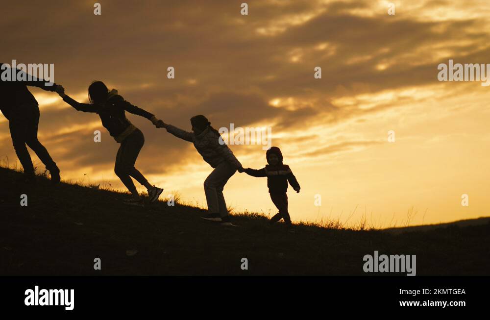 Giving a helping hand. Silhouette of family helping each other on top ...