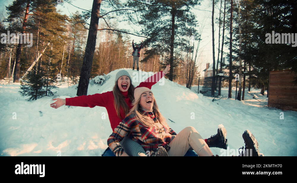 Cinematic slow motion, two beautiful excited happy women sled towards ...