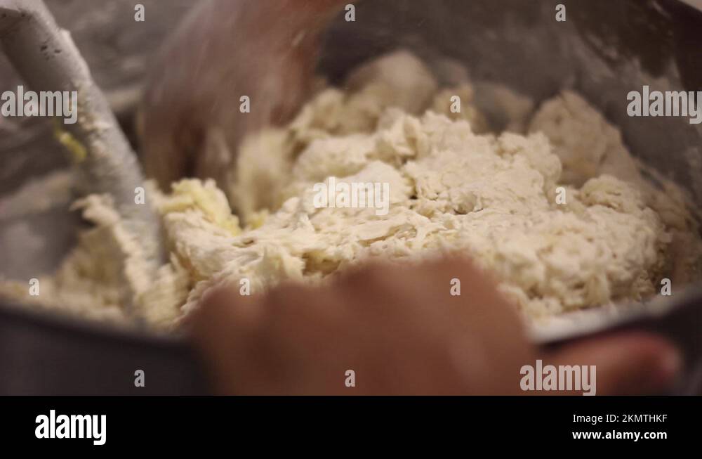 Mixer machine mixing dough and baker rolling in bowl inside bakery ...