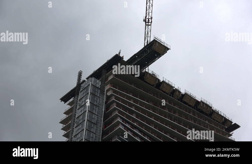 Crane lifting a huge floor slab on top of a condo in a project site ...