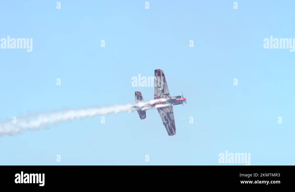 Flying an aerobatic plane upside down leaving white smoke trail behind ...