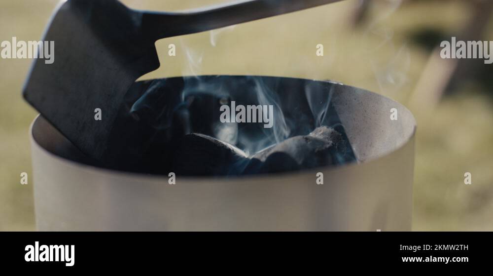 Rake prepare grill charcoal briquettes burning flame fire close up ...