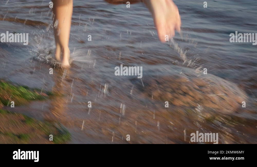 baby legs feet running on beach water through the sun rays. Summer ...