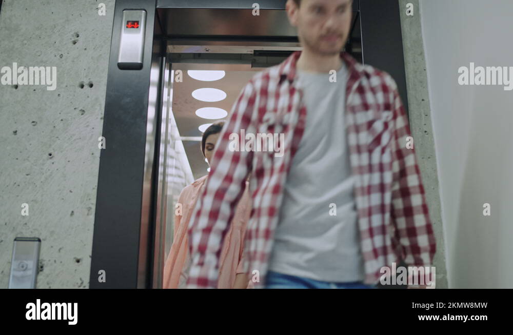 Corporate employees walking out of the elevator in office building ...