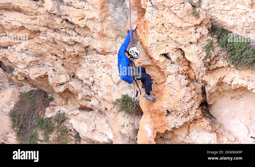 Young Rock Climber looking up while climbing challenging route on cliff ...