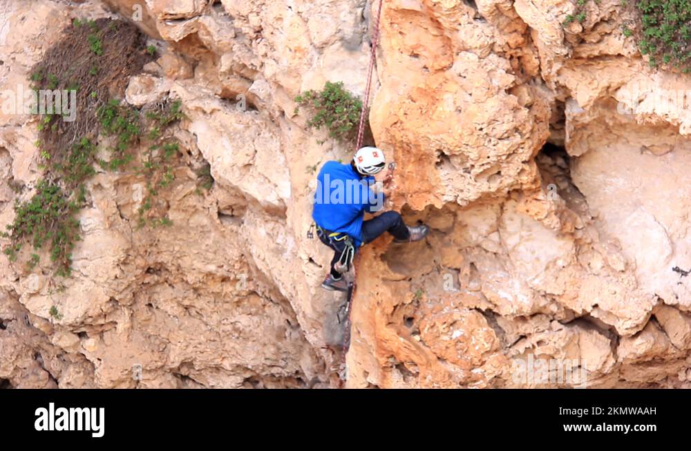 Young Rock Climber looking up while climbing challenging route on cliff ...