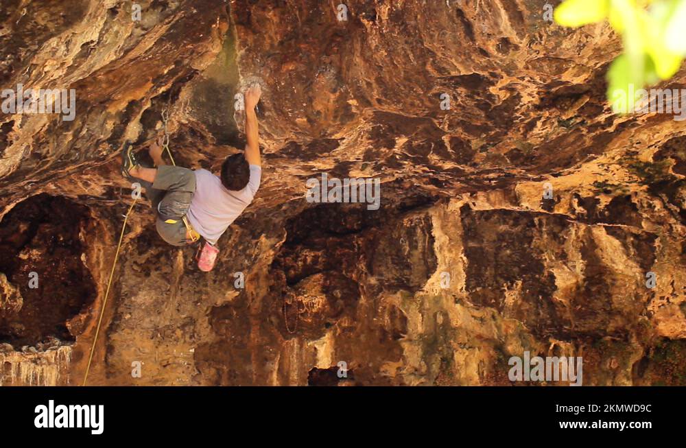 Young Rock Climber looking up while climbing challenging route on cliff ...