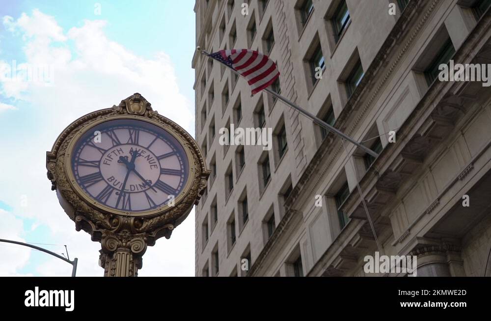 Fifth Avenue building a street clock showing the time. American flag ...