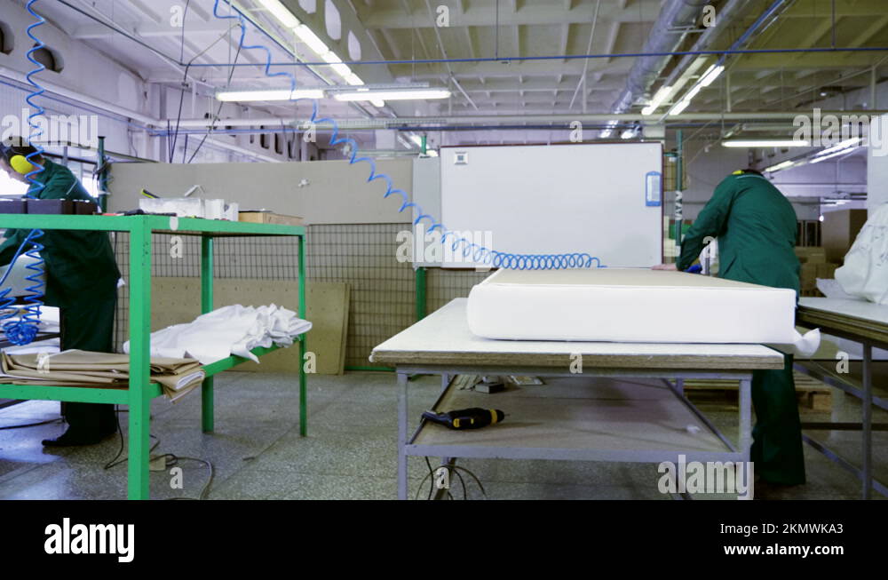 Workers dressed in uniform make a sofa, couch, settee in a furniture ...