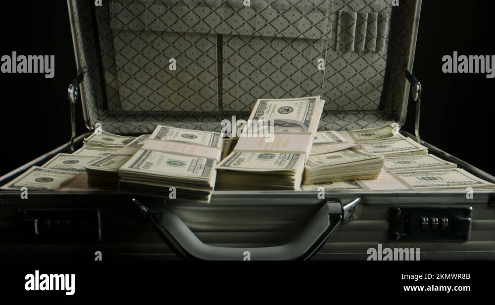 Packs of cash falling into a metal case filled with money. 100 dollar ...