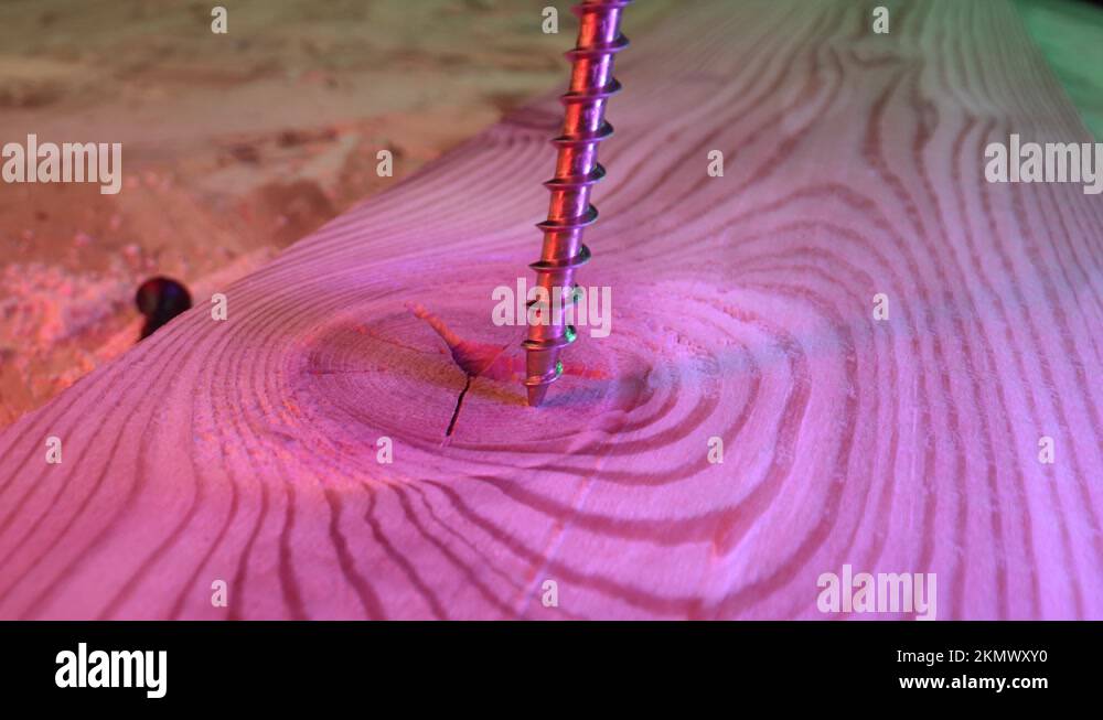 The process of drilling a hole in a wooden board. A thin drill with ...