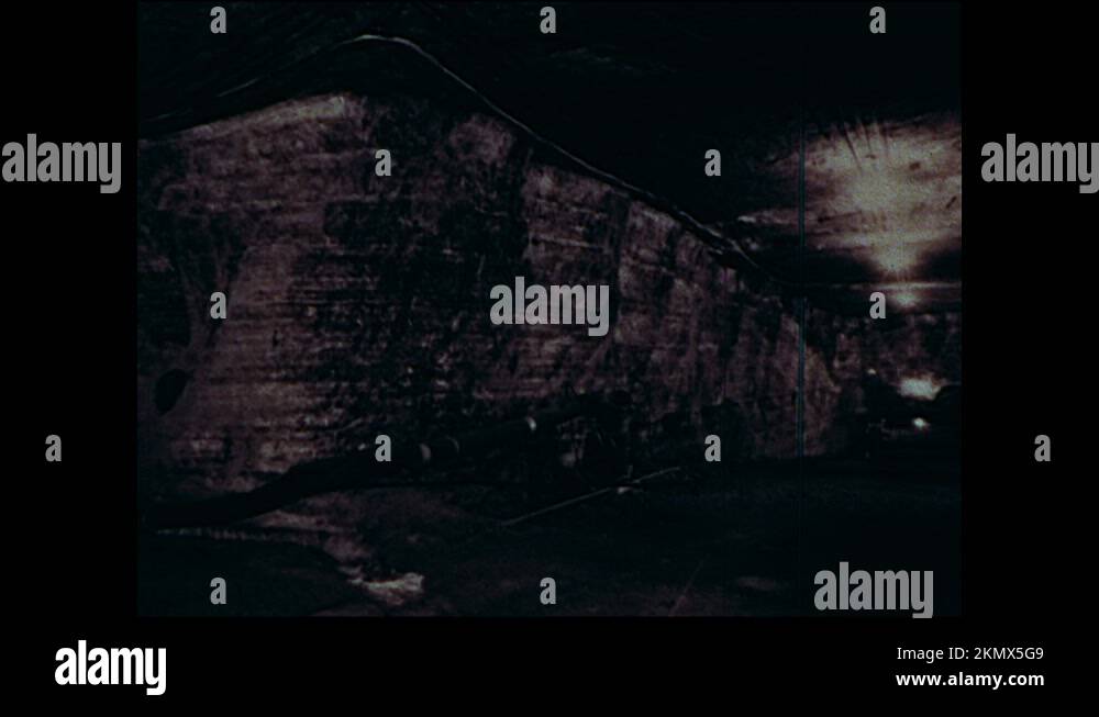 1960s: Lights line ceiling of salt mines. Man adjusts controls on ...