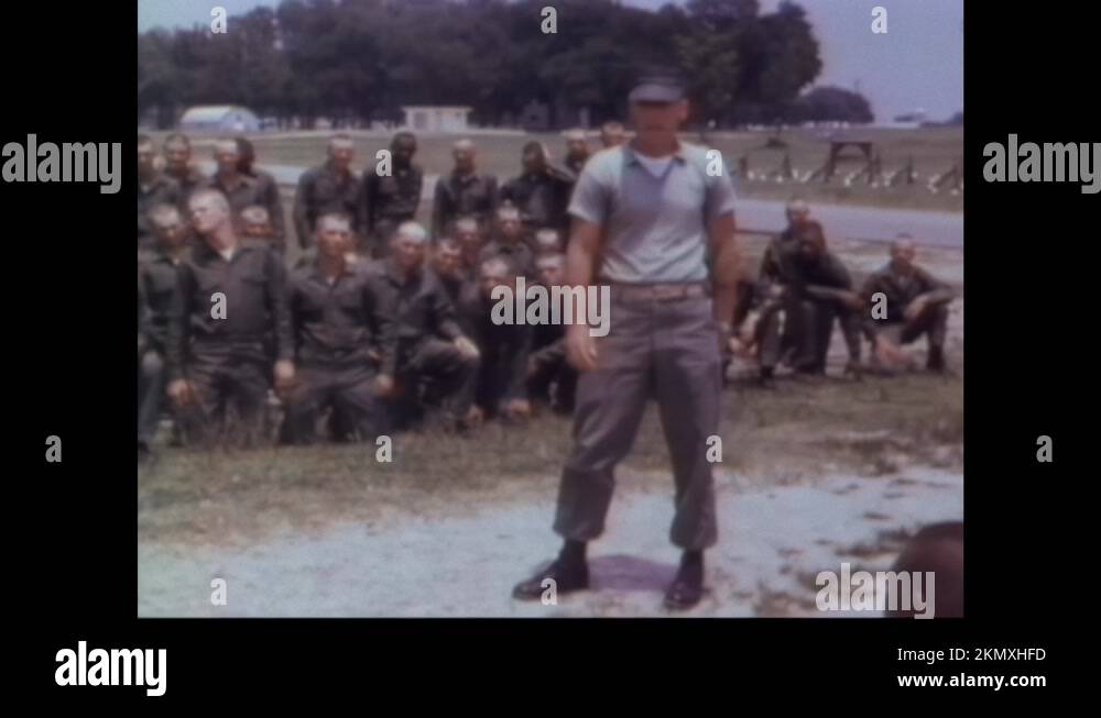1960s: Sergeant instructs men in field. Soldier climbs tall wooden ...