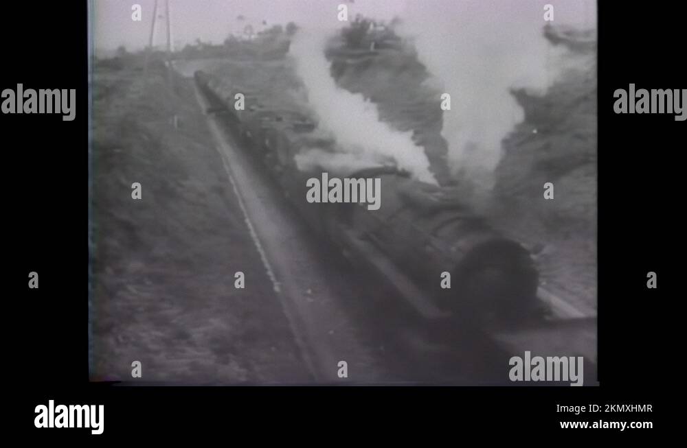 1940s: Locomotive pulls train cars on railroad tracks. Military ...