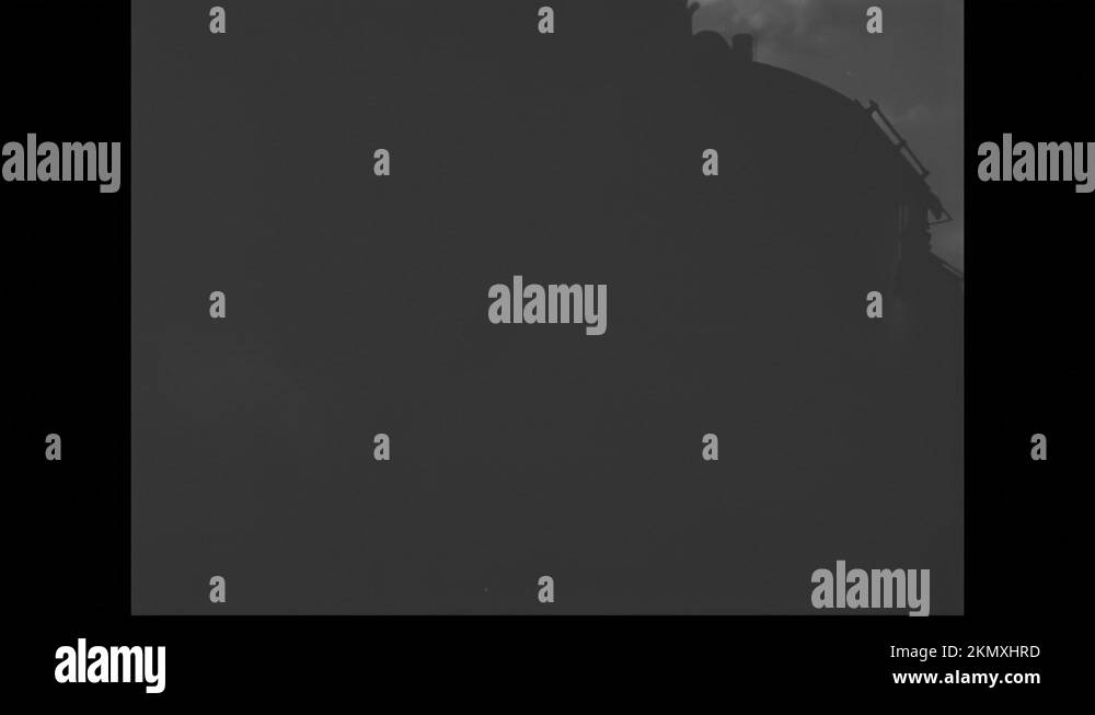 1950s: Locomotive pulling train cars on railroad tracks leaves factory ...