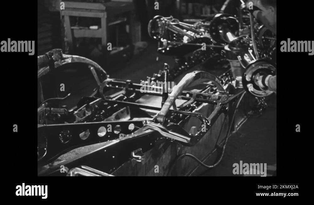 1950s: Vehicle chassis roll down assembly line in automotive factory ...