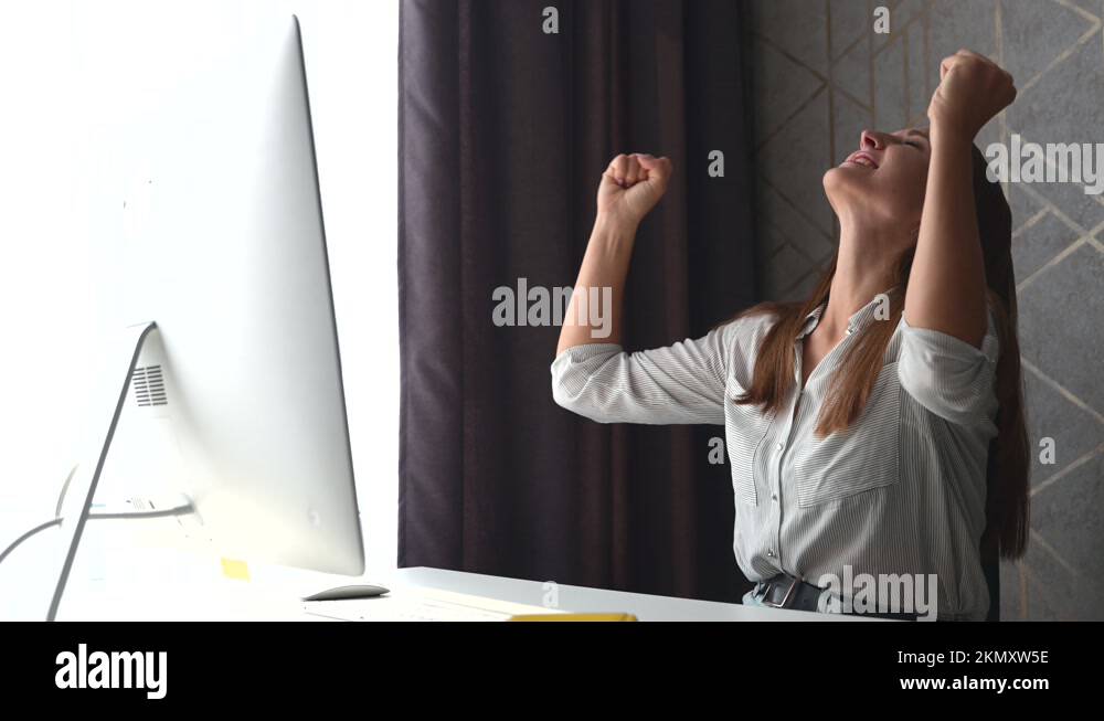 Hilarious overjoyed young woman scream yes and raising hands up in ...