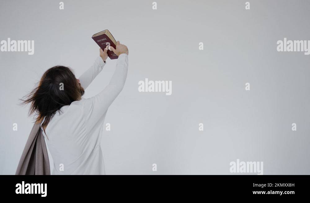 Jesus raised the Bible in his hands above his head on a white ...