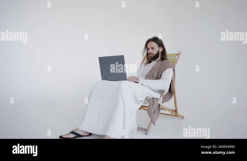Jesus sits in a schizlong and works at a computer on a white background ...