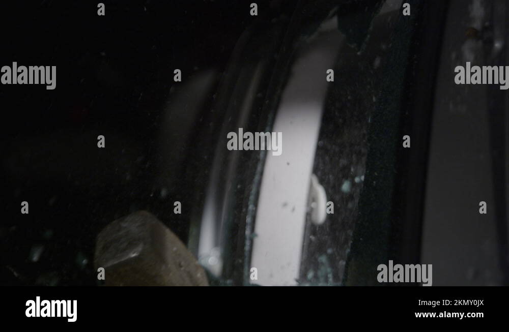 Close up sledge hammer shattering glass windshield of car, dark scene ...