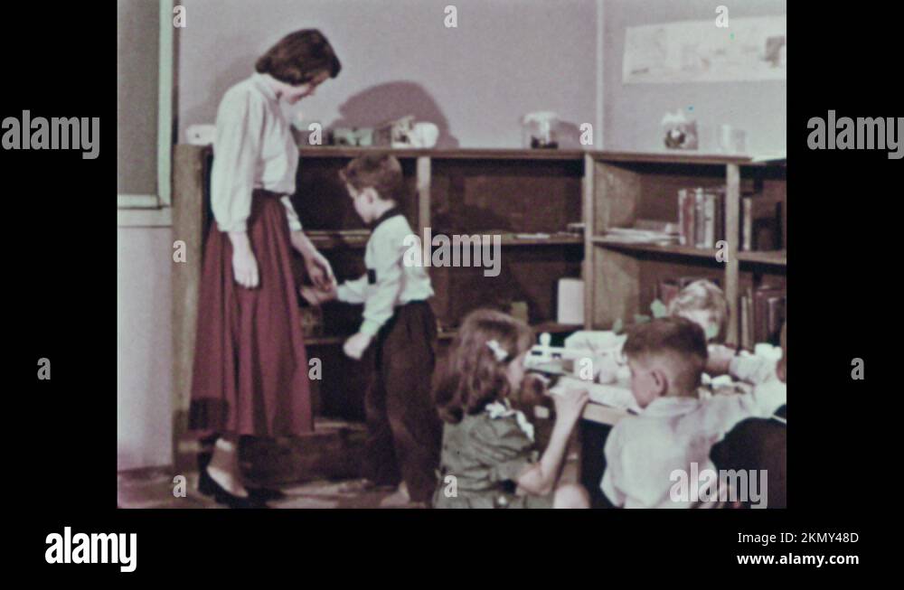 1950s: Teacher talks to students at diorama table in classroom. Man and ...