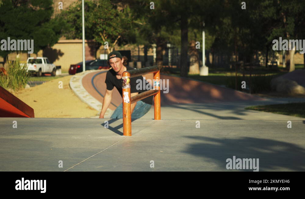 Skateboarder hops and slides along a rail at a skate park. Locked off ...
