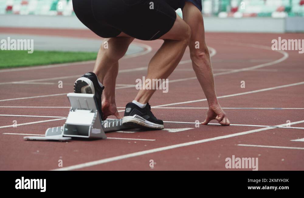 Stadium, man sprinter is preparing for the start of a training run in ...