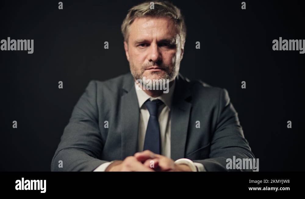 Portrait of a criminal in business suit handcuffed in interrogation ...