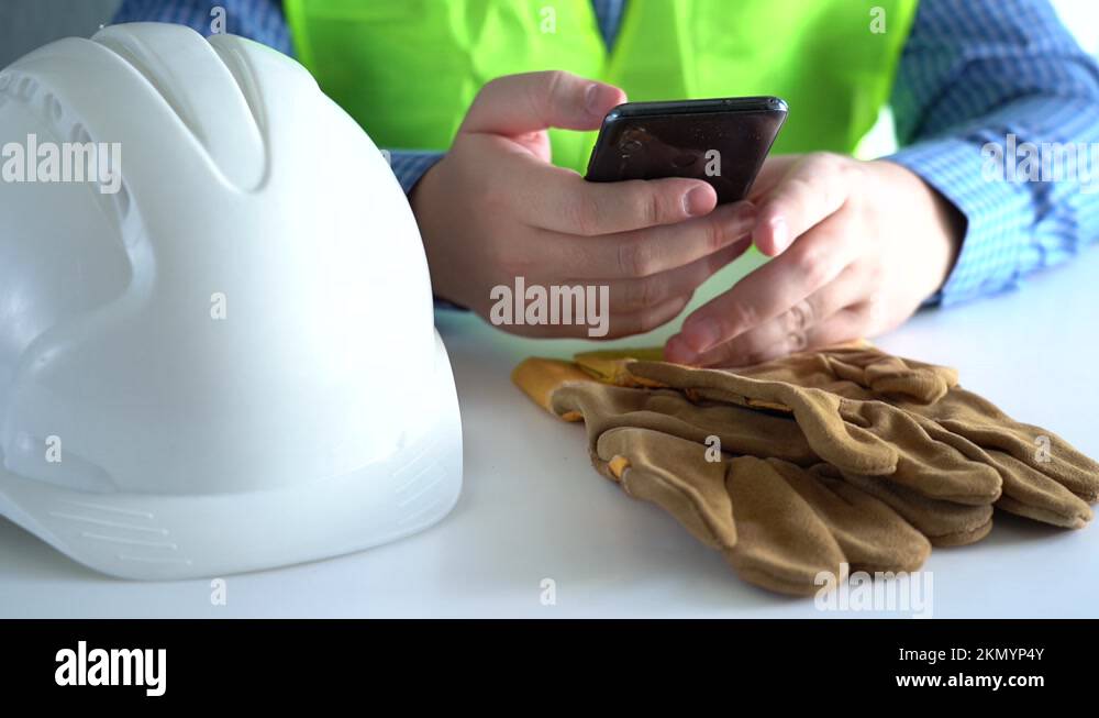 Hands of a male builder with a smartphone. A builder reads messages and ...