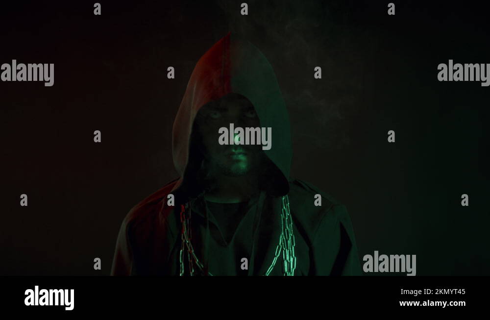 Evil sorcerer wearing black suit on dark background. Portrait of wicked ...