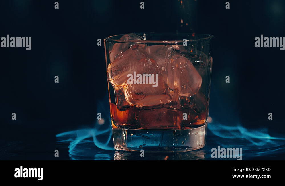 Whiskey is poured into glass of ice,whiskey splashes on bar against, blue flames Stock Video ...
